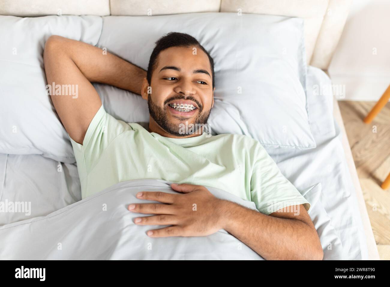 Top view of happy african american guy laying in bed Stock Photo - Alamy