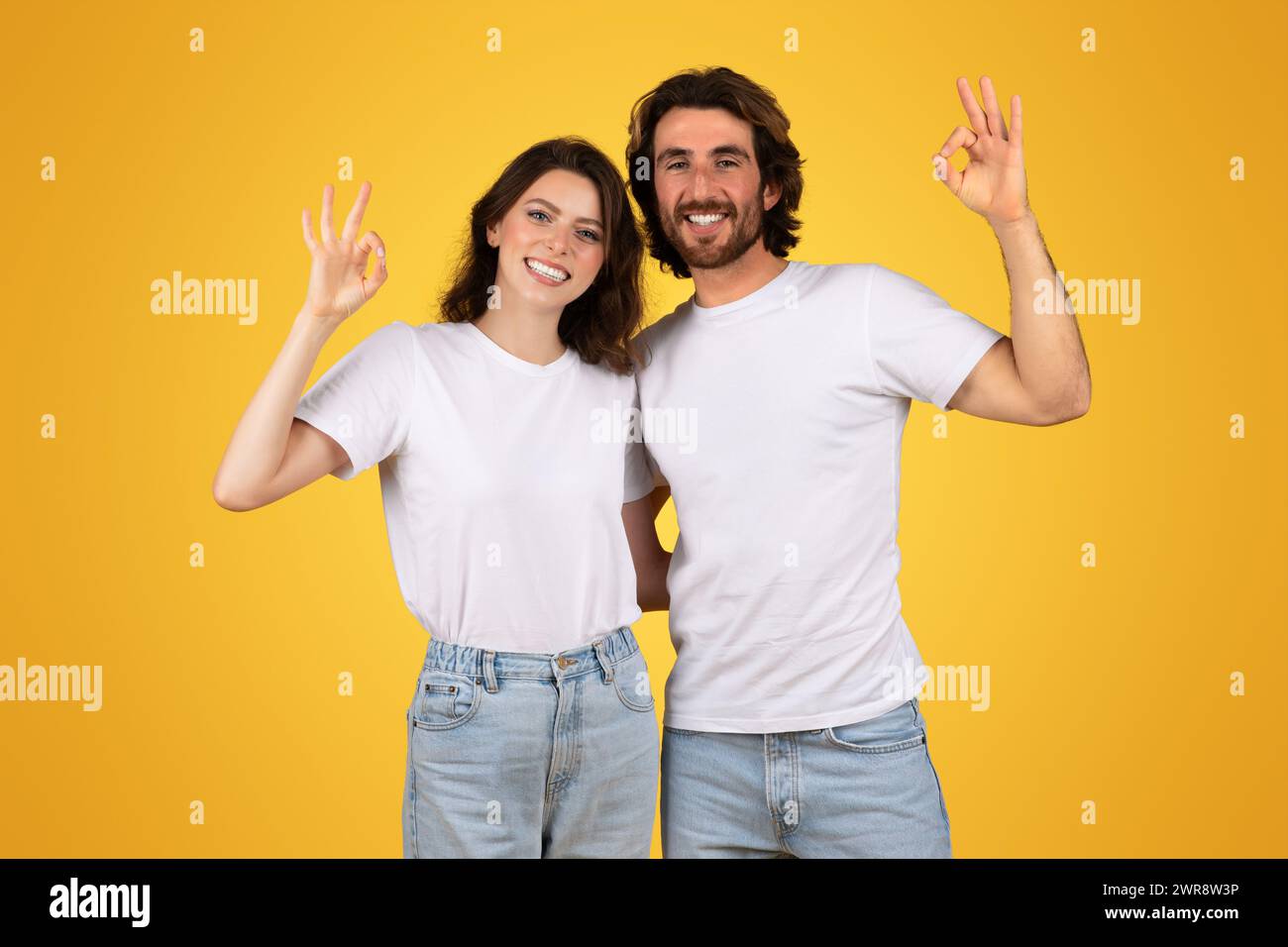 Joyful man and woman in white t-shirts and jeans making the OK hand ...