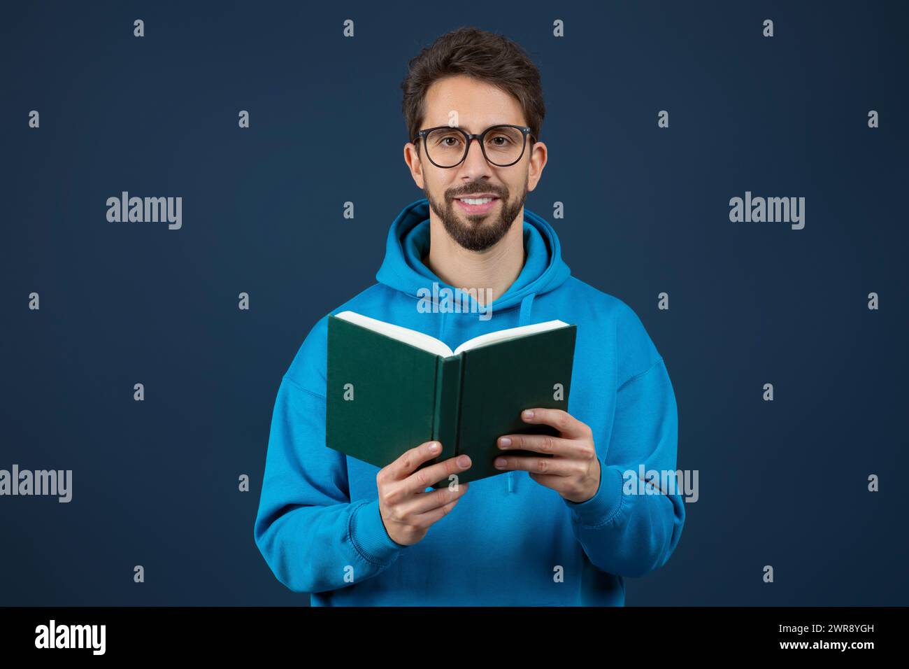Intelligent-looking man wearing eyeglasses holding green book and ...