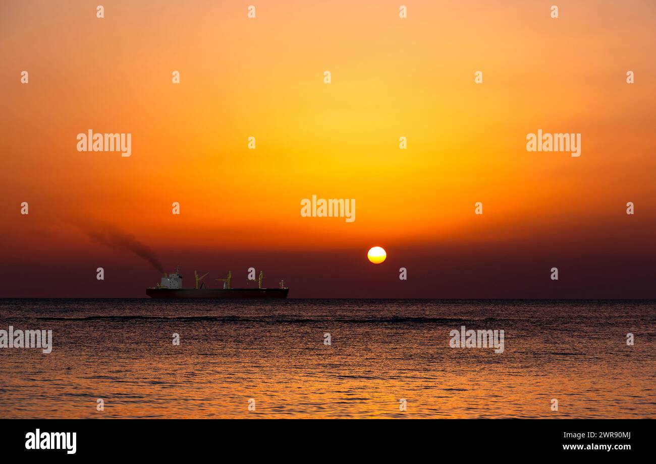 A silhouette of a cargo ship at sunset Stock Photo - Alamy