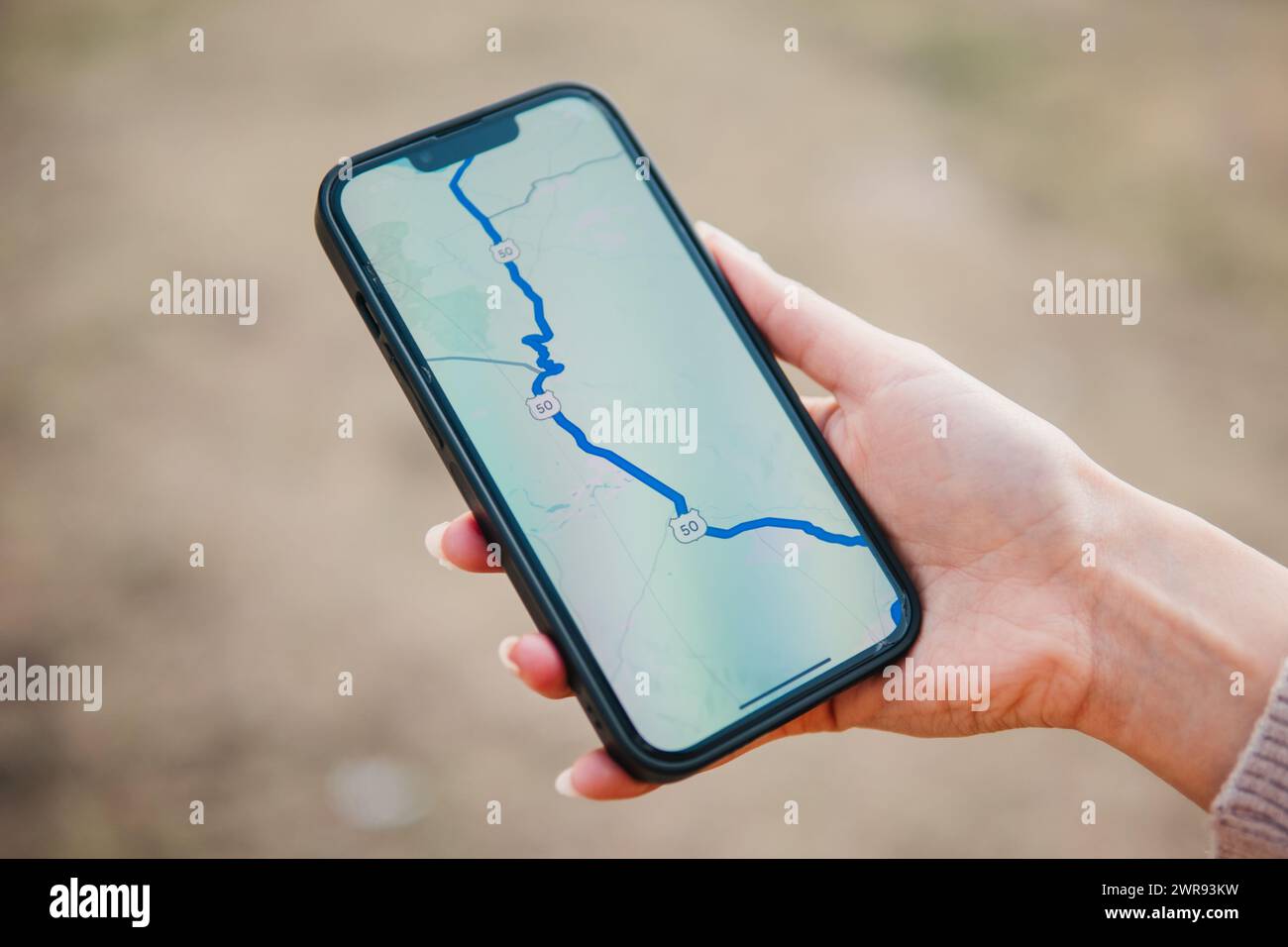 A close-up of a hand holding a smartphone displaying a GPS navigation ...