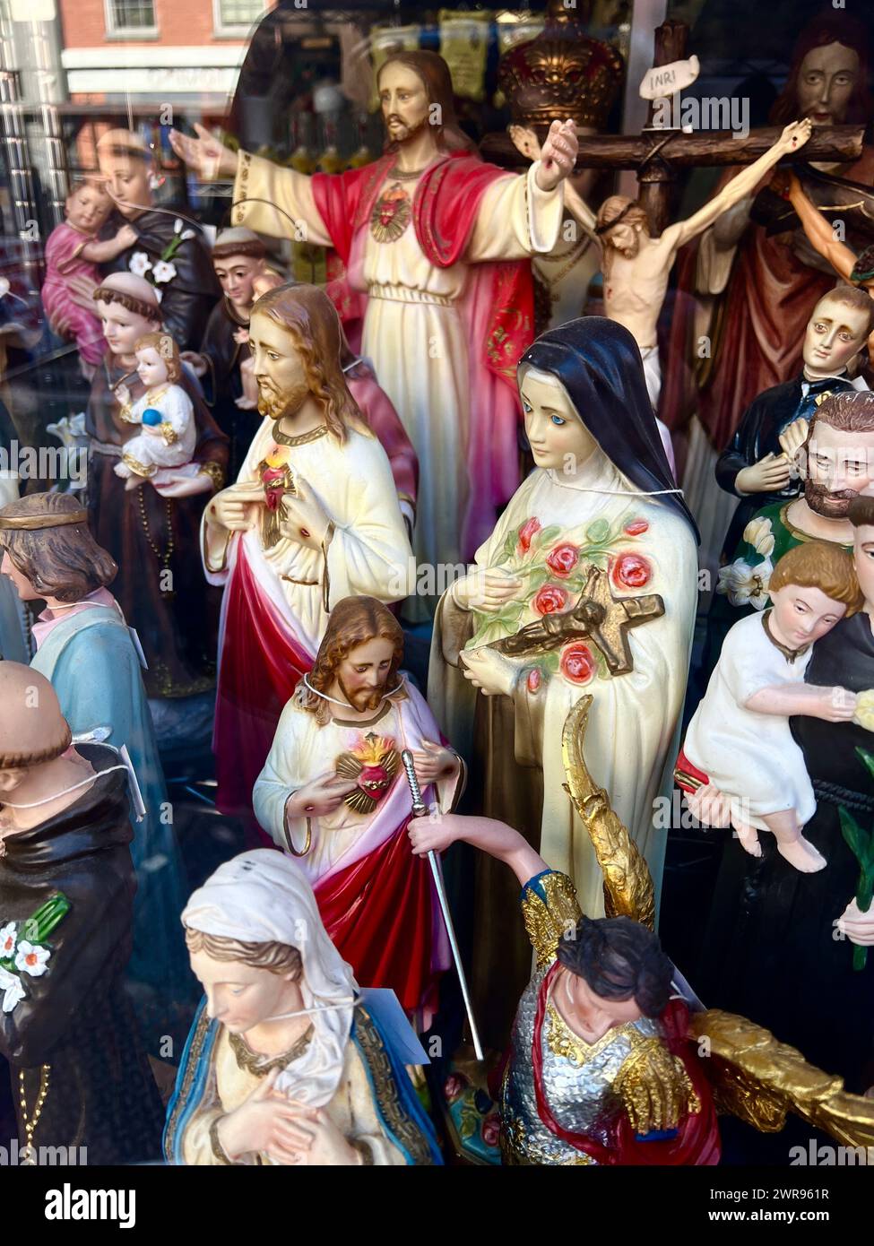 A variety of religious Catholic statues displayed in a store window on ...