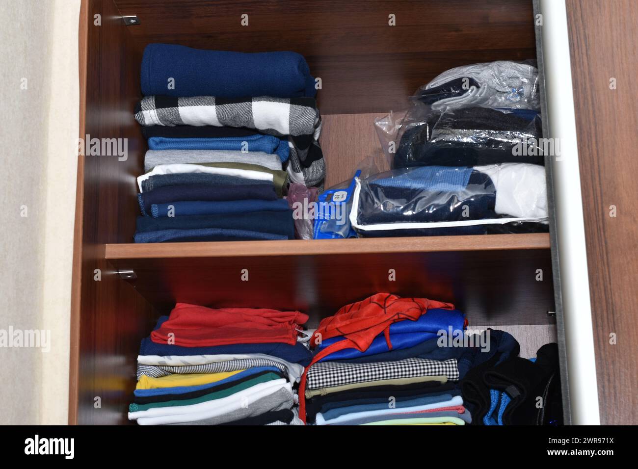 Through the open door in the closet, clothes lying on the shelves can ...