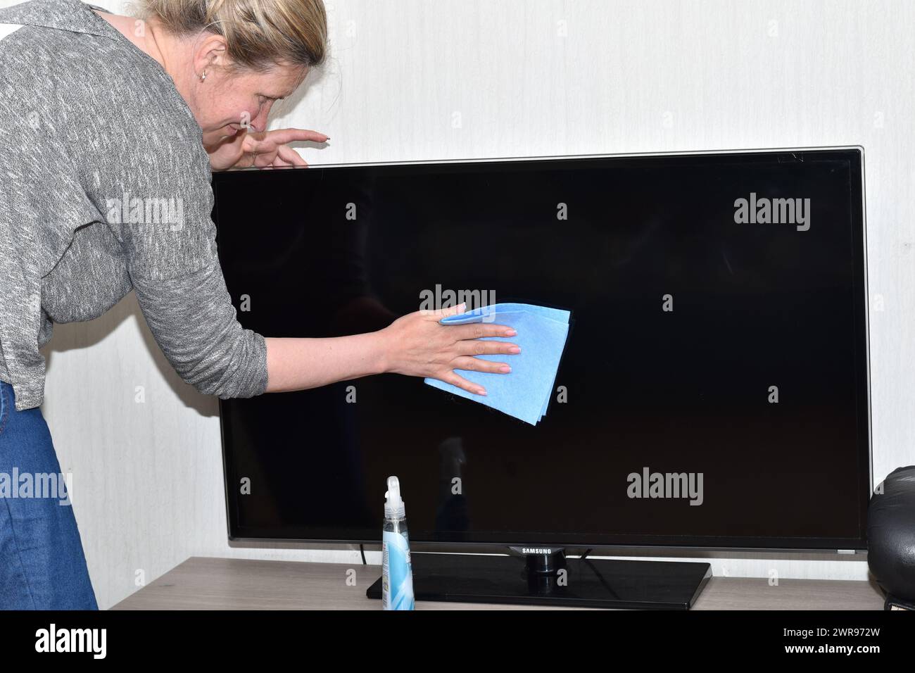 The hostess is cleaning the apartment, she wipes dust from the TV ...