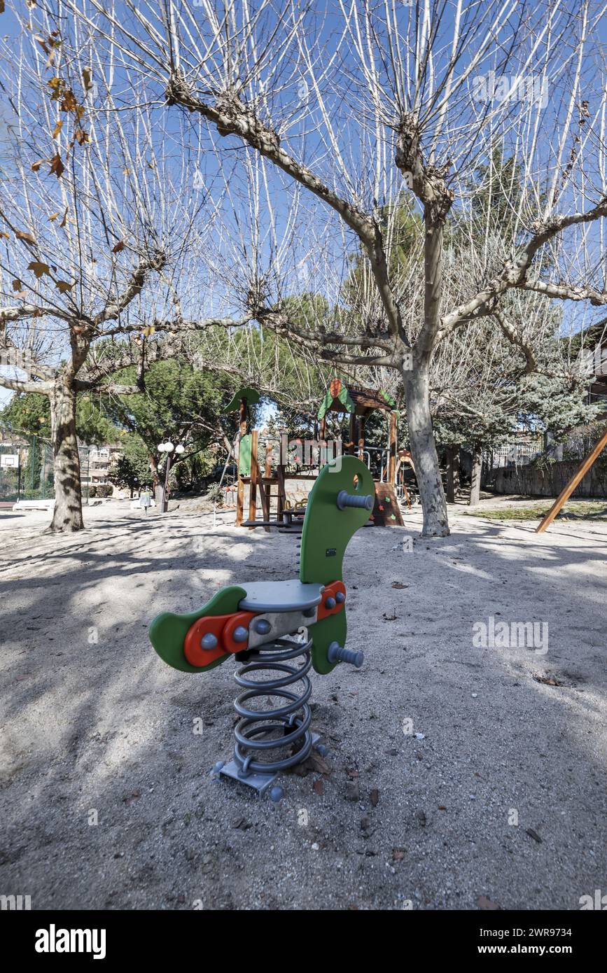 Play with a spring in a playground with sandy floors and leafless trees ...