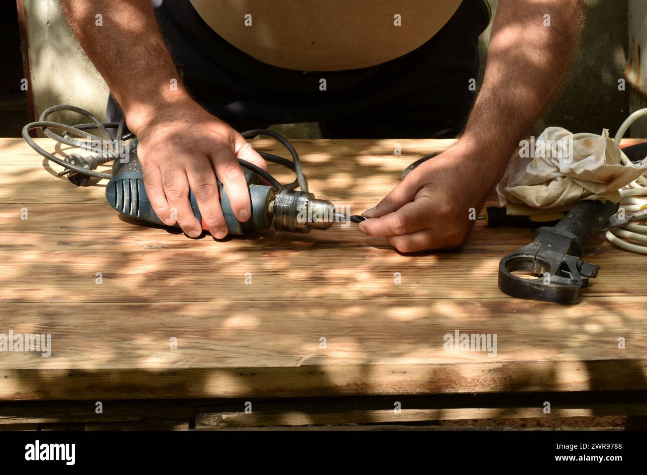 The carpenter has a drill tool on the table, he prepares it for work ...