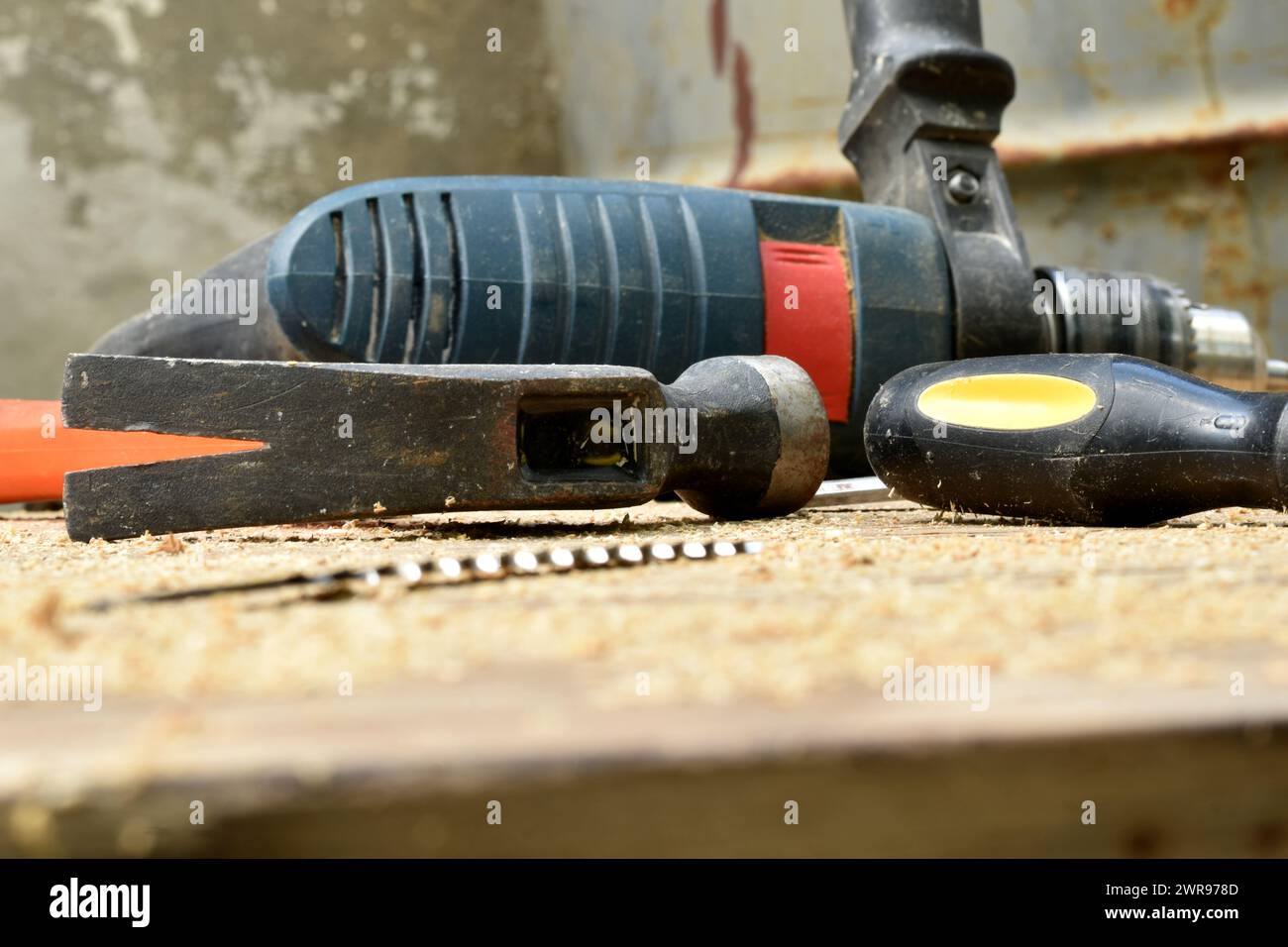 The picture shows a tool lying on the table, a drill, a hammer and a ...