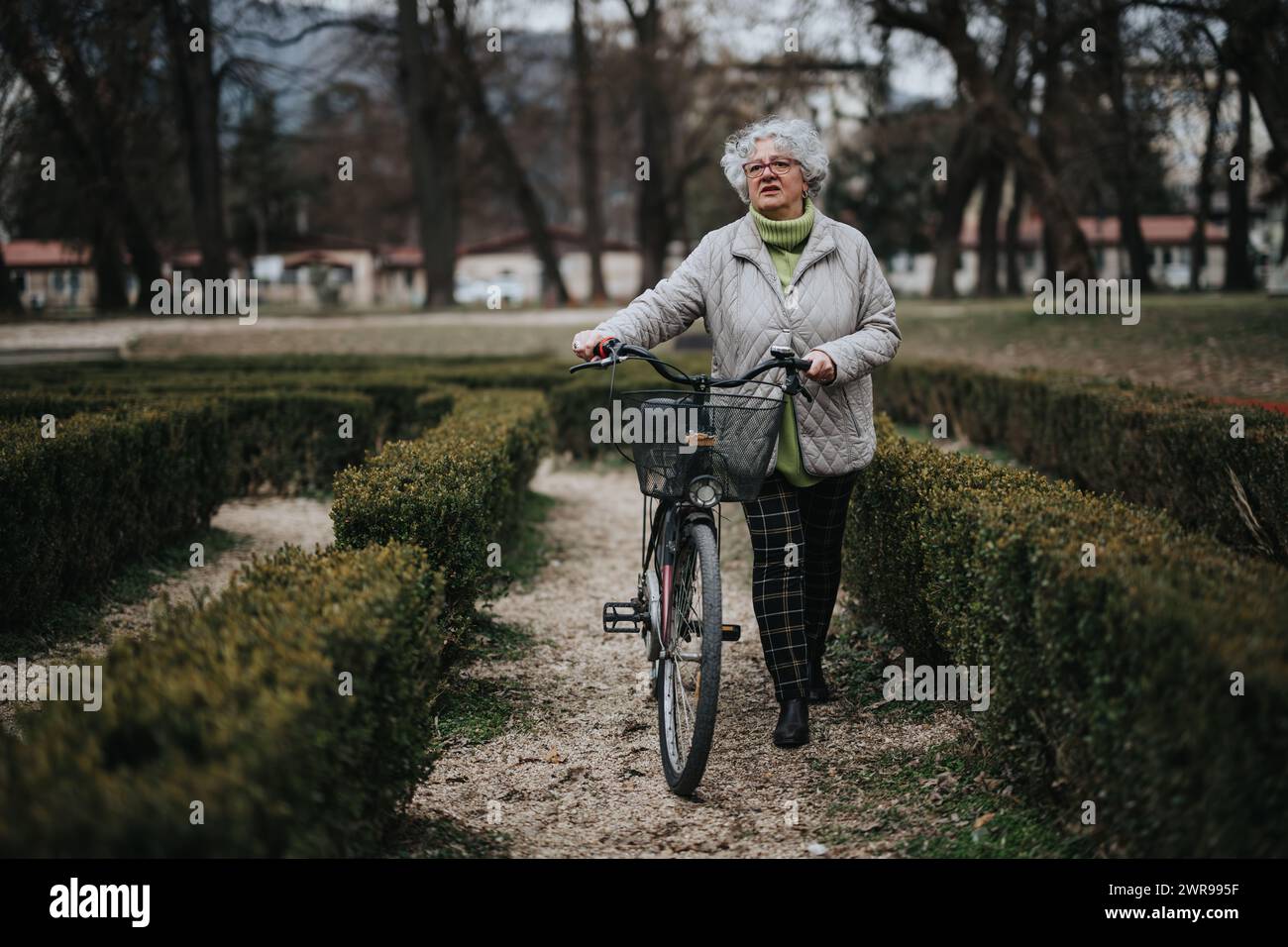 Active senior woman enjoying a bike ride in a park, promoting healthy ...