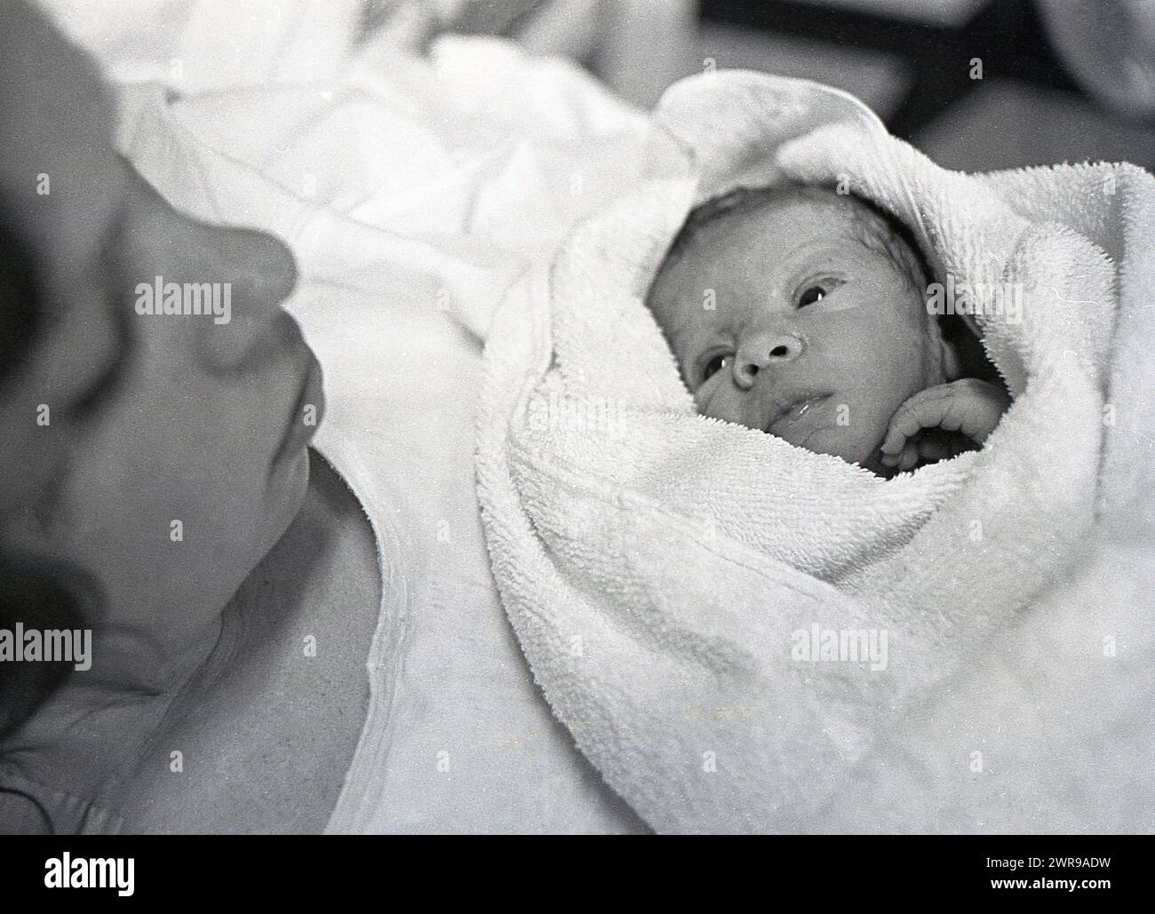 1970s, historical, new mother looking at jer newly born baby wrapped in ...