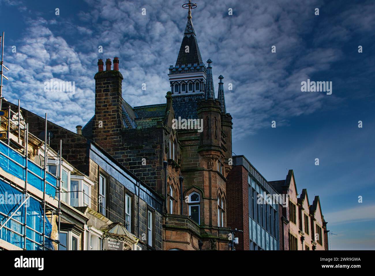 Historic architecture with a spire against a dramatic sky, flanked by ...
