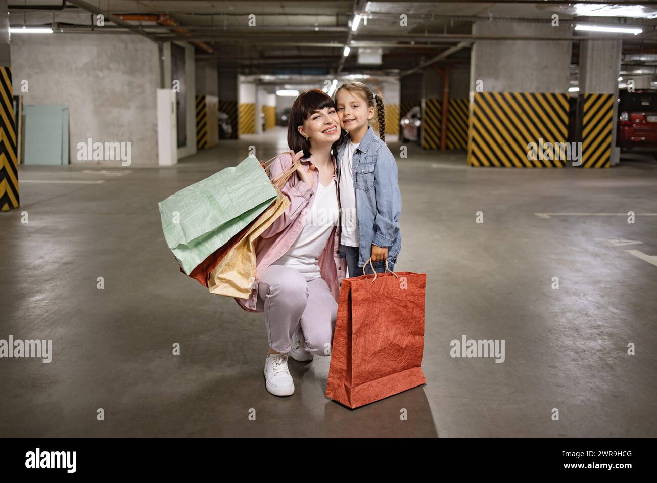 Caucasian mother and her young daughter in underground parking lot ...