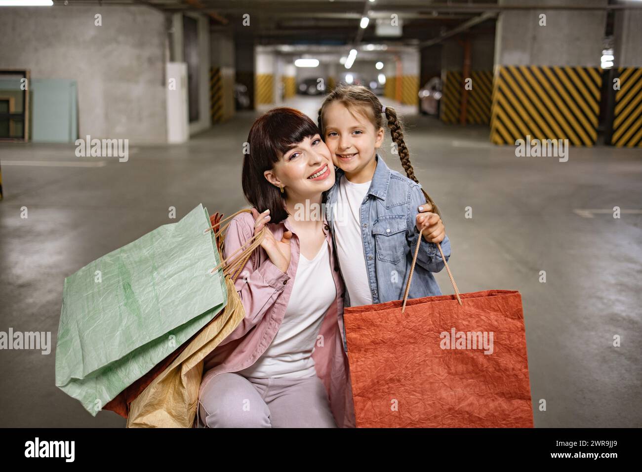 Happy woman with little child hugging while holding colored bags with ...