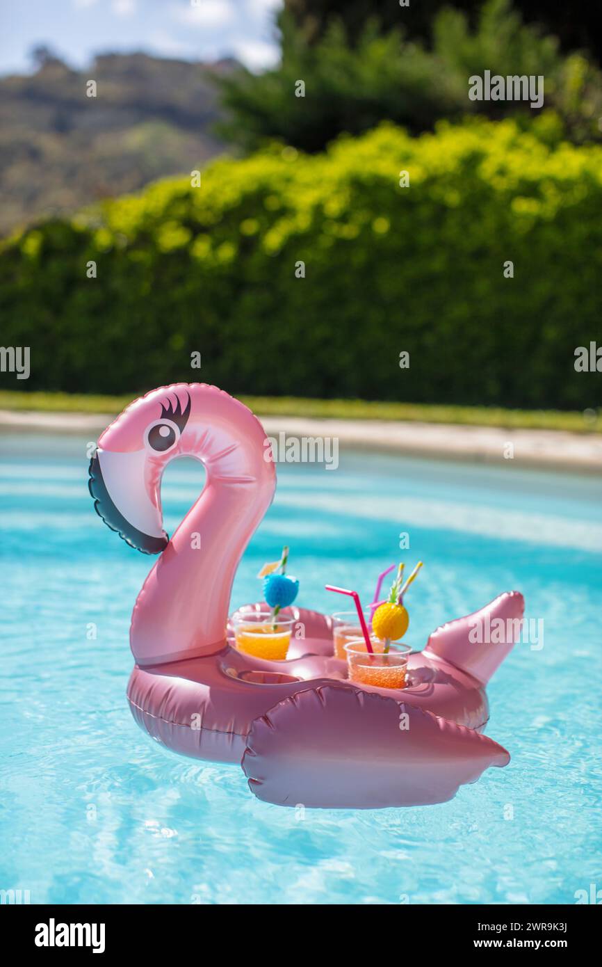 Pink inflatable flamingo float on blue water in the swimming pool with ...