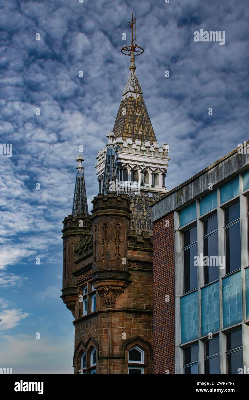 Historic tower with spire against a dramatic cloudy sky, juxtaposed ...