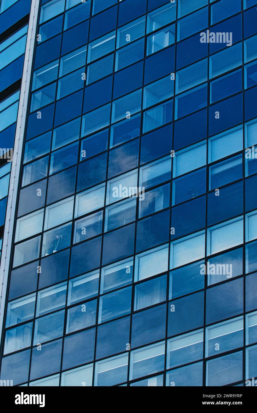 Modern glass building facade reflecting blue sky with clouds ...