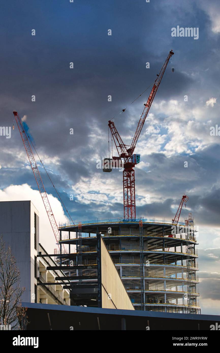 Construction site with cranes against a dramatic cloudy sky ...
