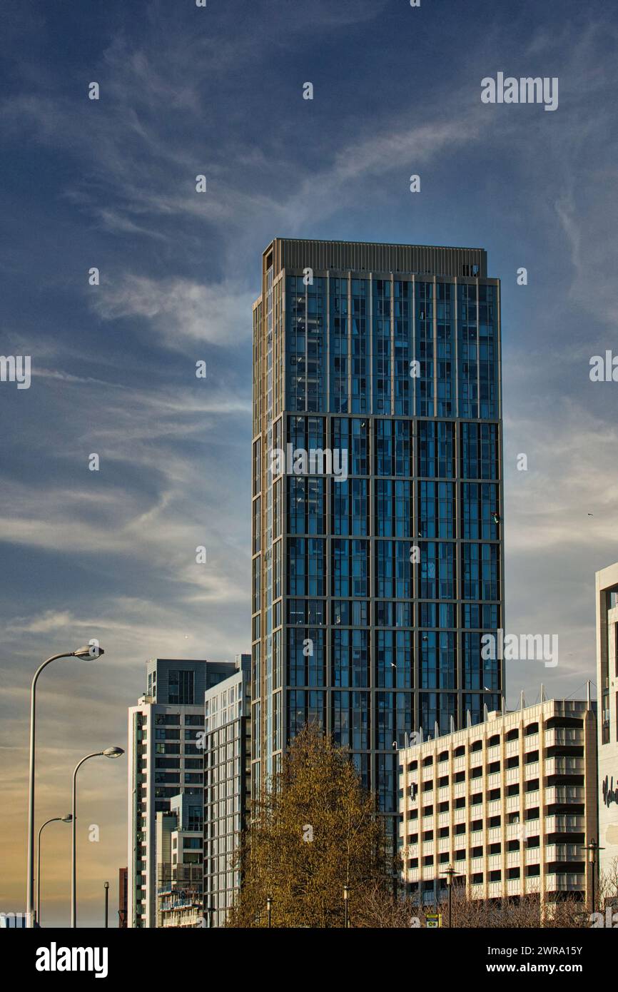 Modern glass skyscraper against a blue sky with clouds, surrounded by ...