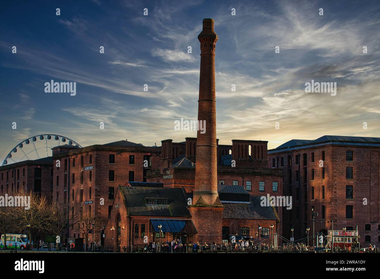 Historic red brick buildings with tall chimney against a dramatic ...