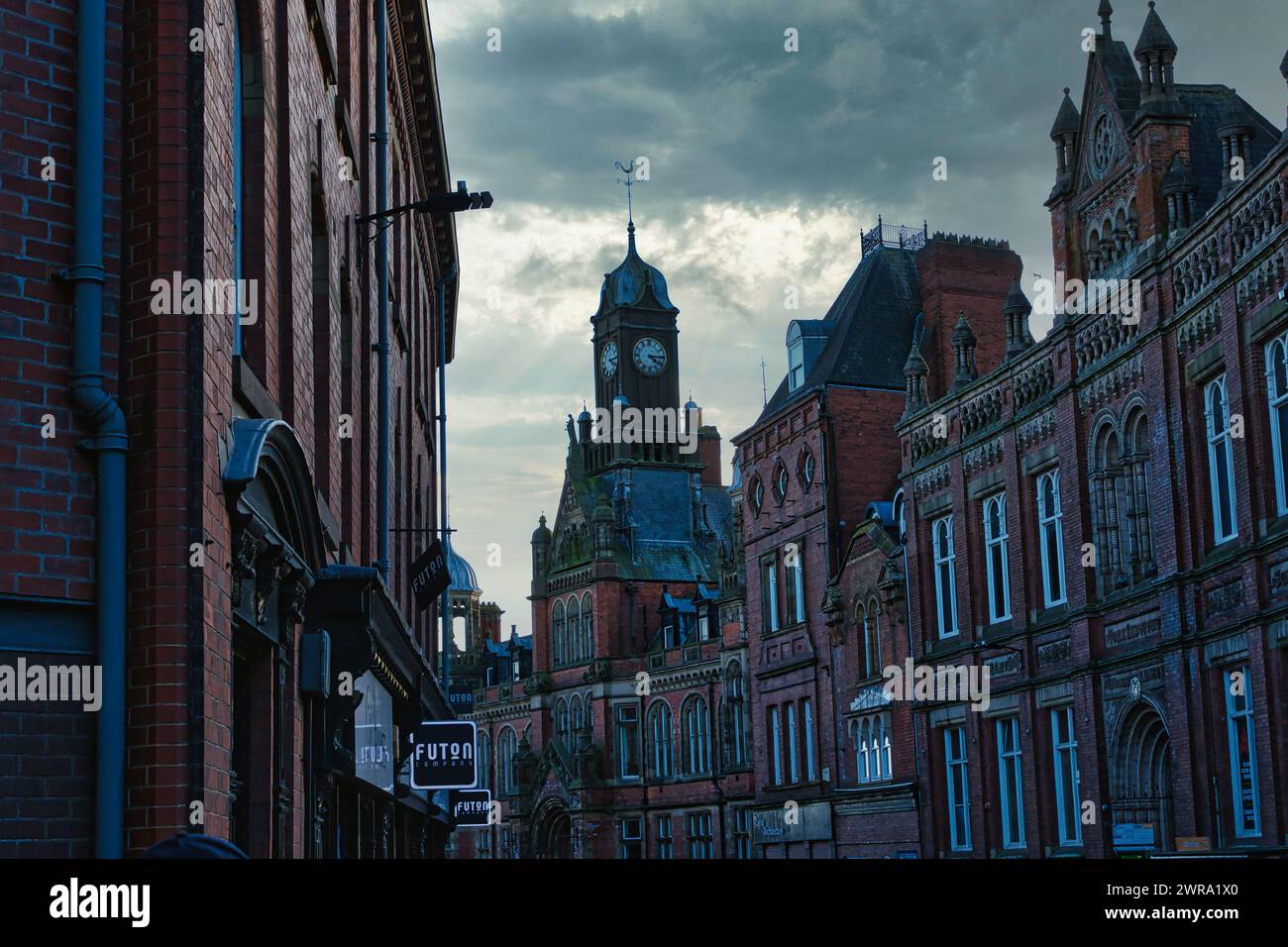 Historic European cityscape with clock tower at dusk, moody sky, and ...