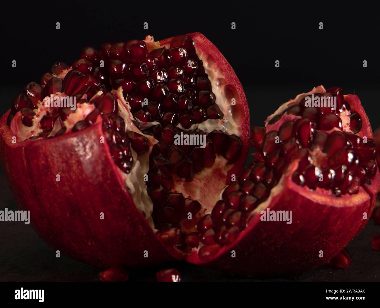 fresh open pomegranate with seeds on a black background Stock Photo - Alamy