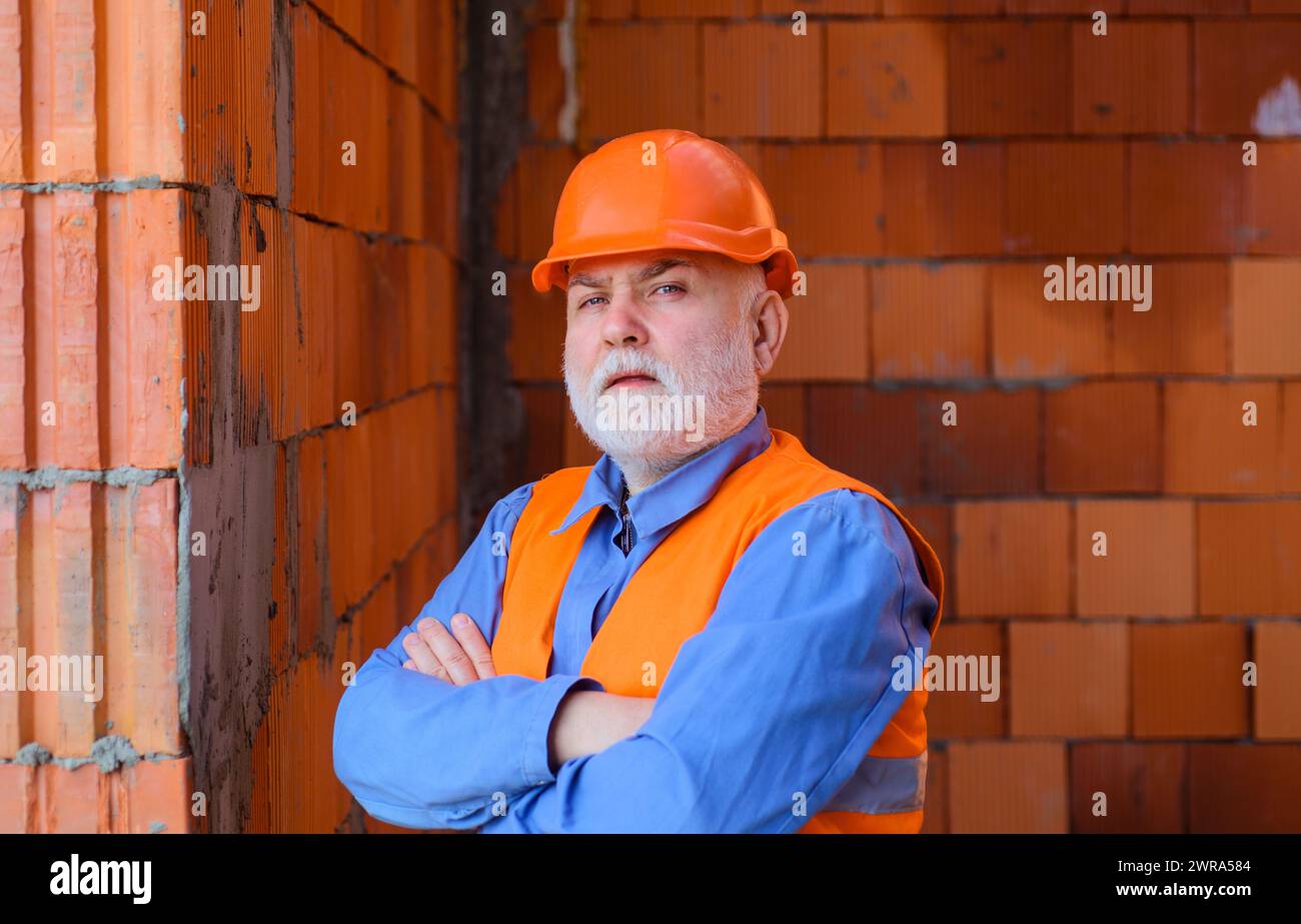 Portrait serious handsome builder in hard hat working on house ...