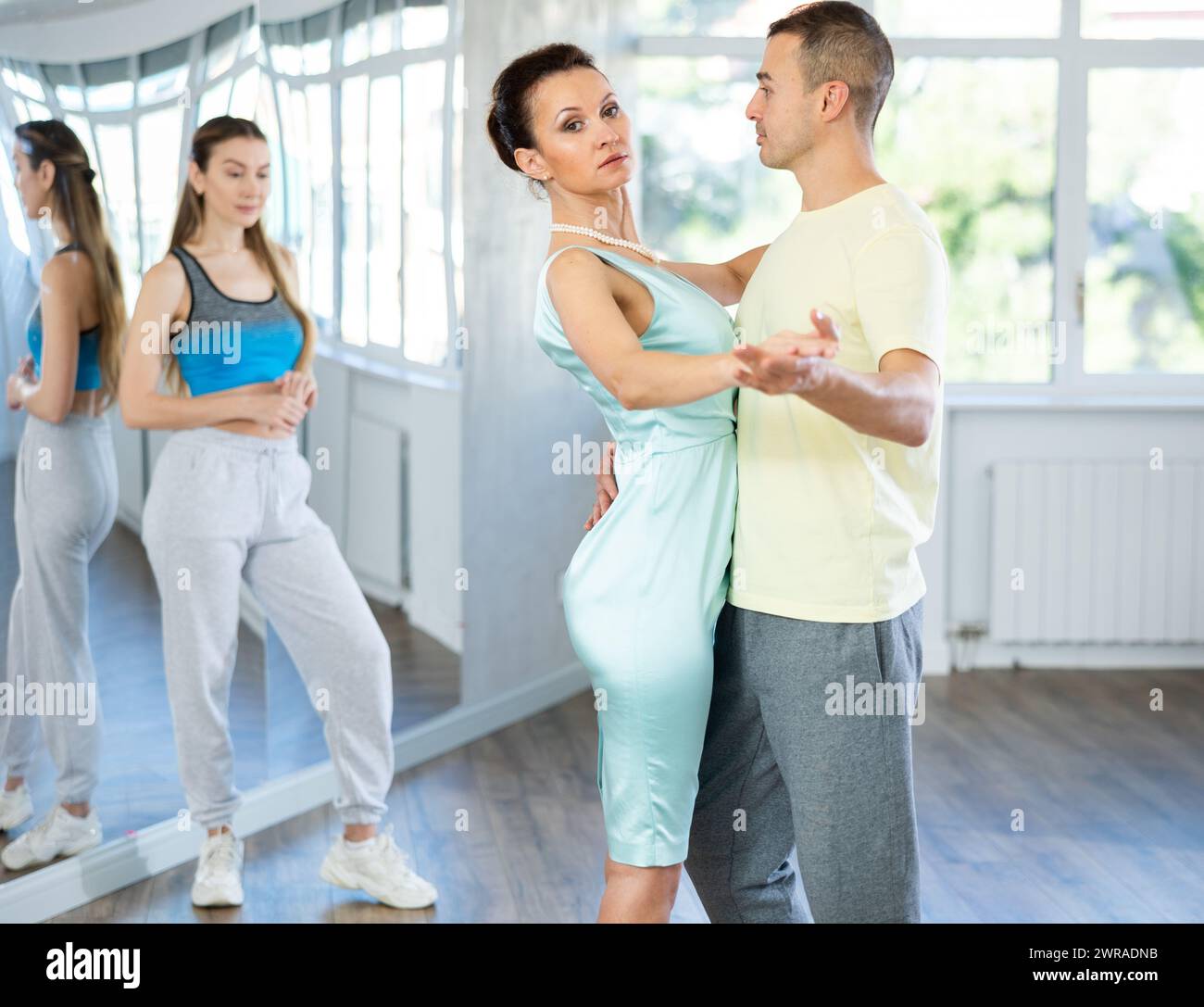 Coach, paired with man student, shows master class and explains technique of waltz dance Stock ...