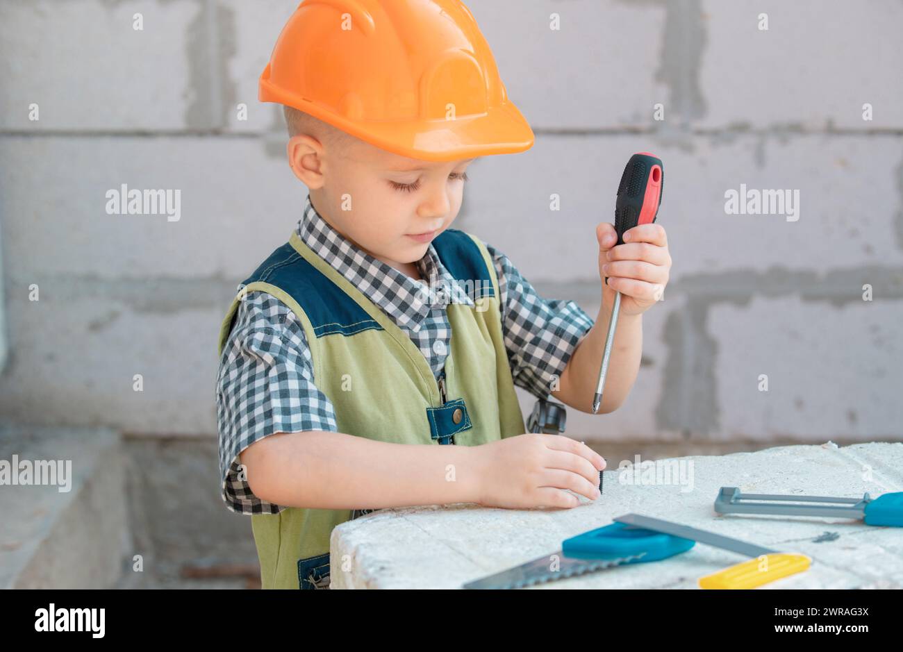Little boy holding screwdriver. Kid twists bolt with screwdriver ...