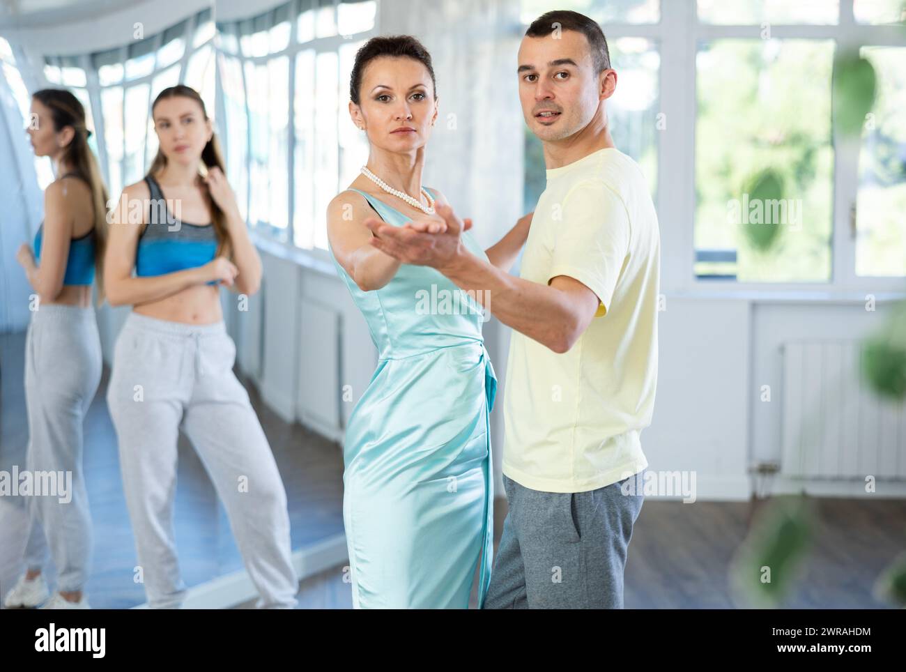 Coach, paired with man student, shows master class and explains technique of waltz dance Stock ...