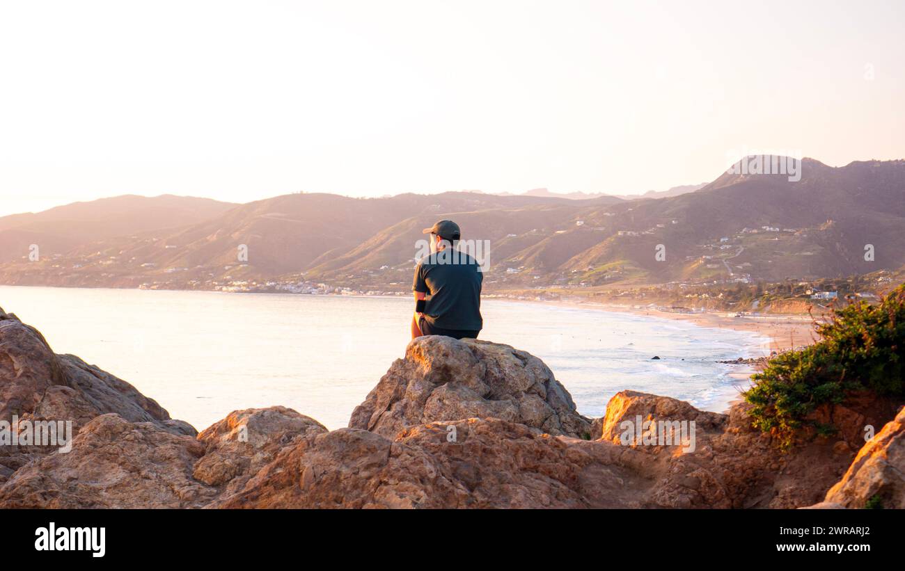 Young man sitting on a rock hi-res stock photography and images - Alamy