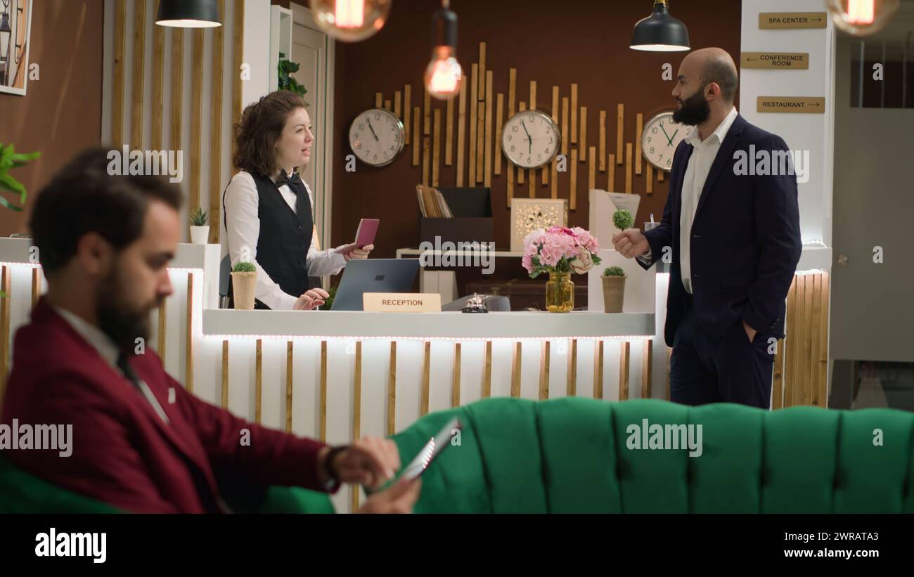 Employee checking guest passport to validate online room reservation ...