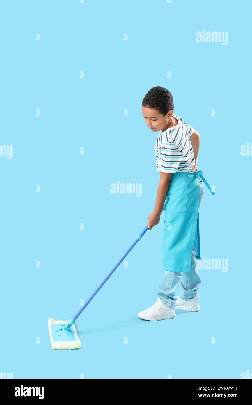 Cute little African-American boy mopping floor on blue background Stock ...