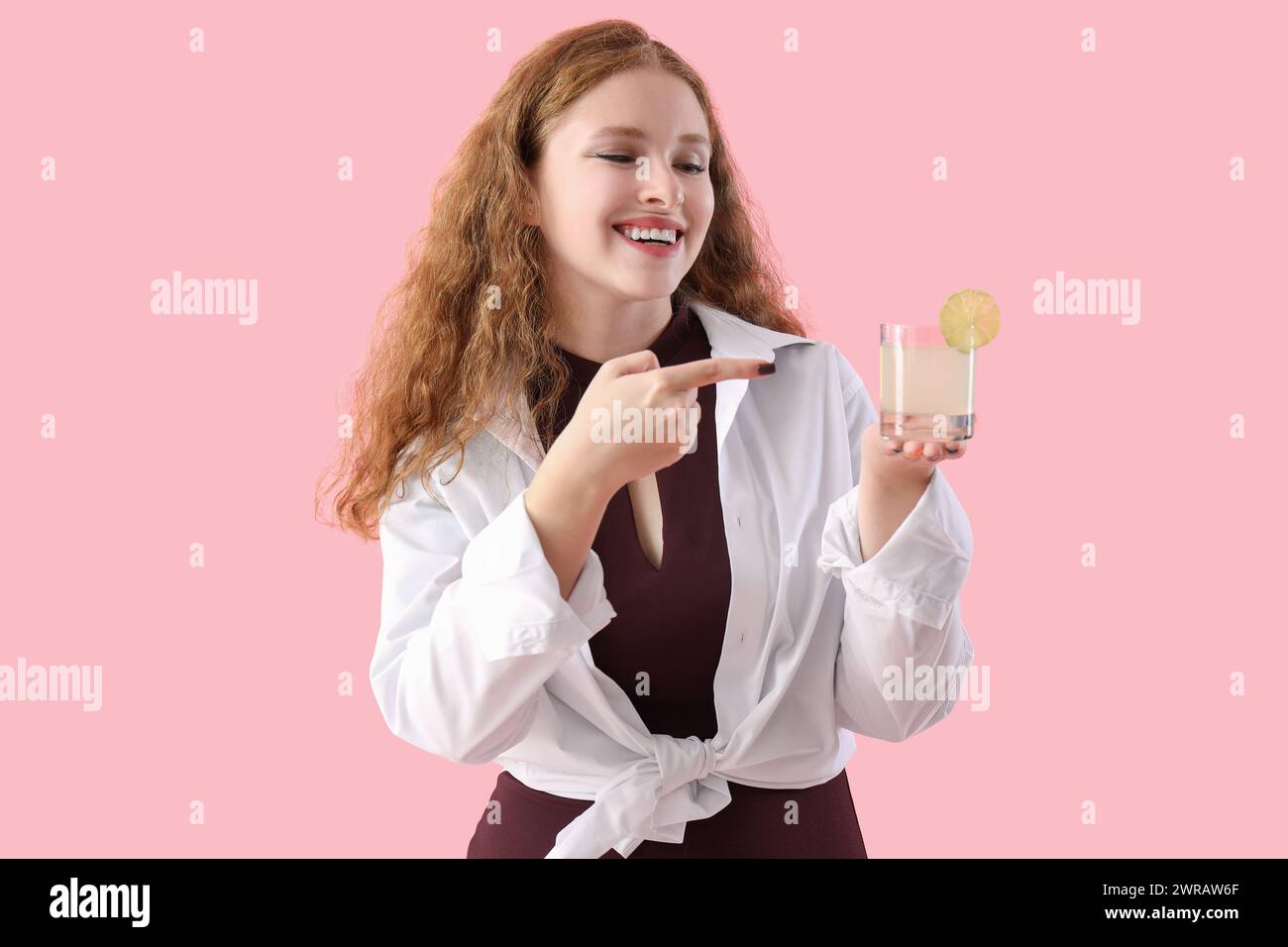 Female bartender pointing at cocktail on pink background Stock Photo ...
