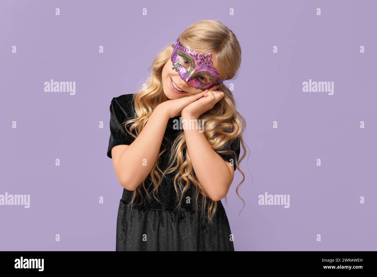 Happy little girl wearing carnival mask on lilac background Stock Photo ...