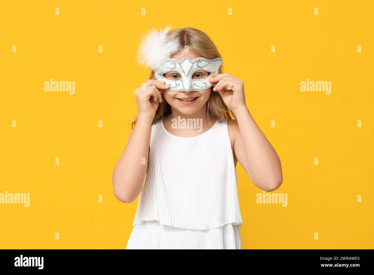 Happy little girl wearing carnival mask on yellow background Stock ...