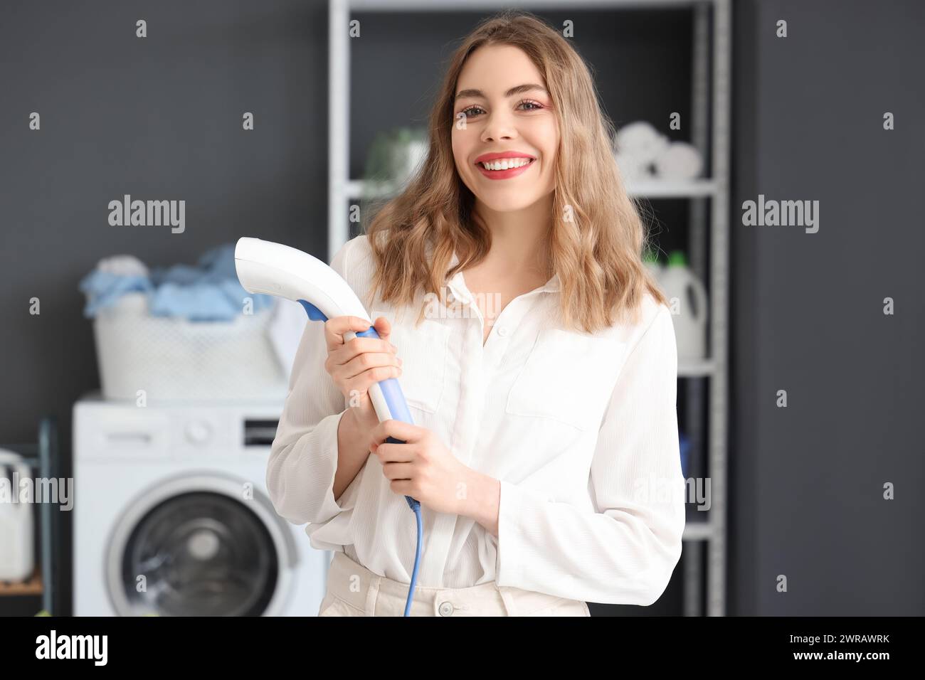 Pretty young woman with modern garment steamer in laundry room Stock ...