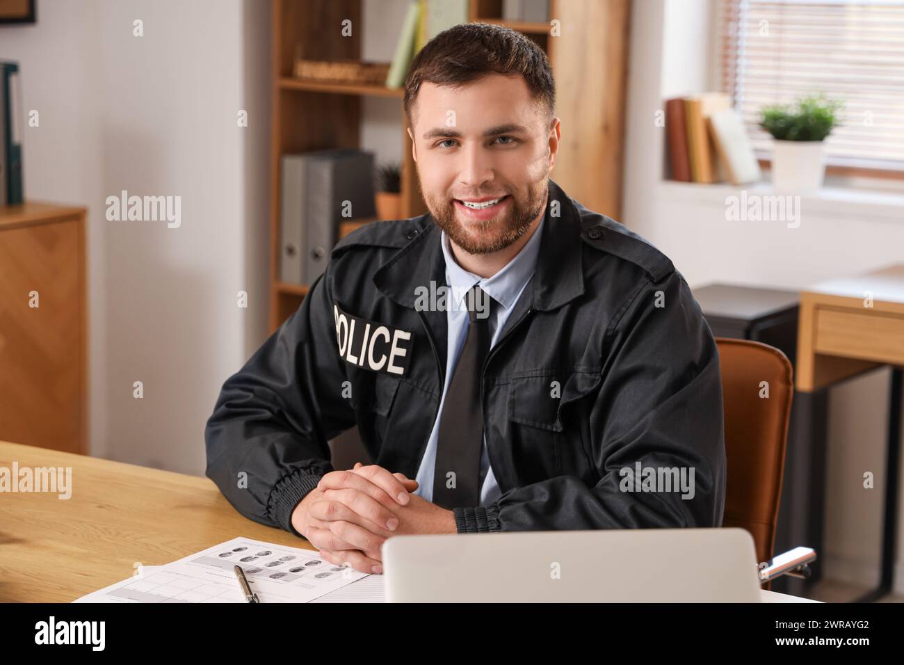 Male police officer sitting in office Stock Photo - Alamy