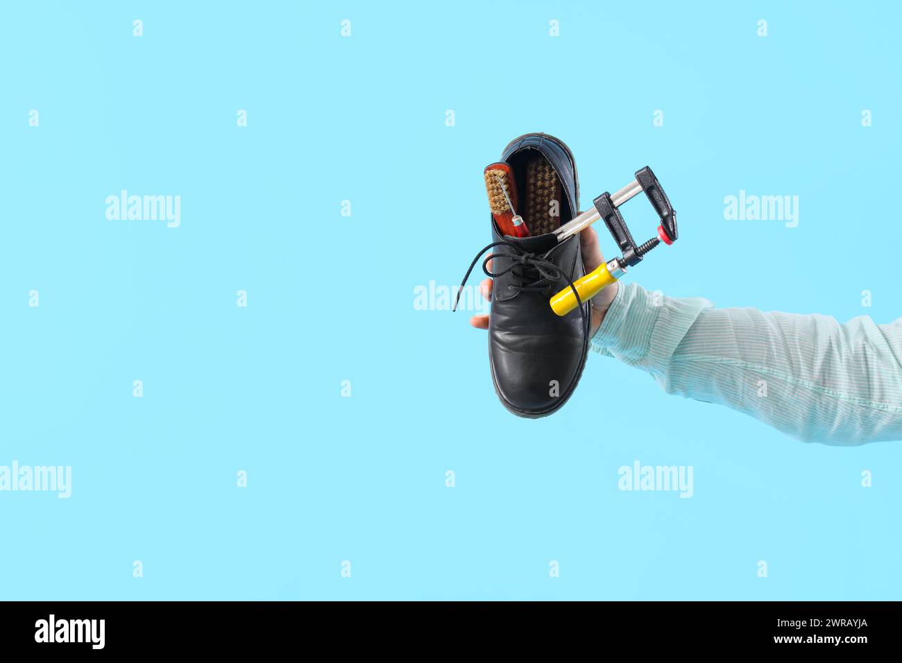 Male shoemaker holding boot with tools on blue background Stock Photo ...