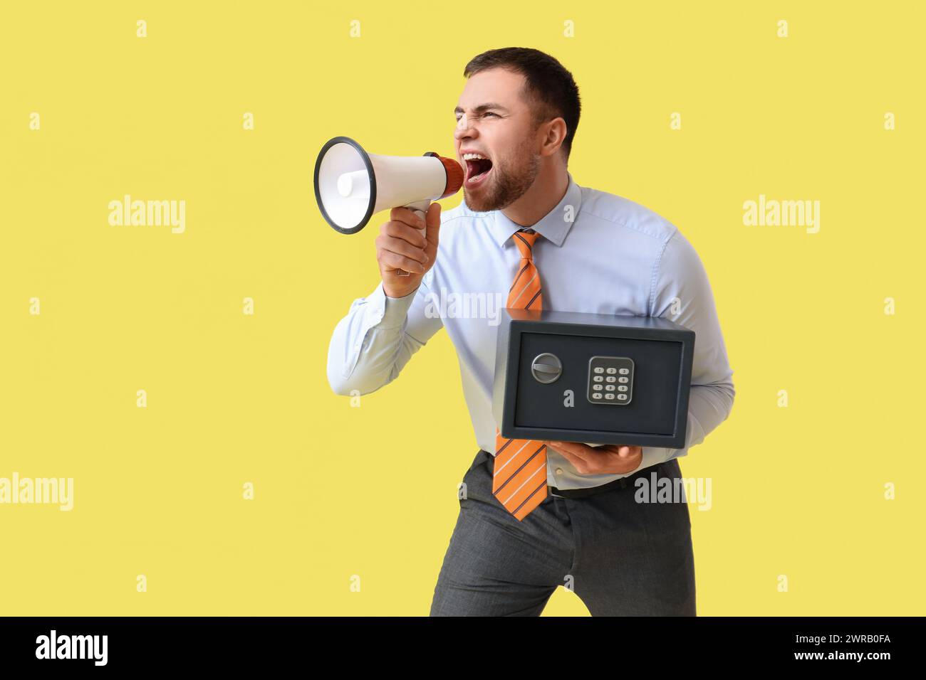Young man with safe box and megaphone screaming on yellow background ...