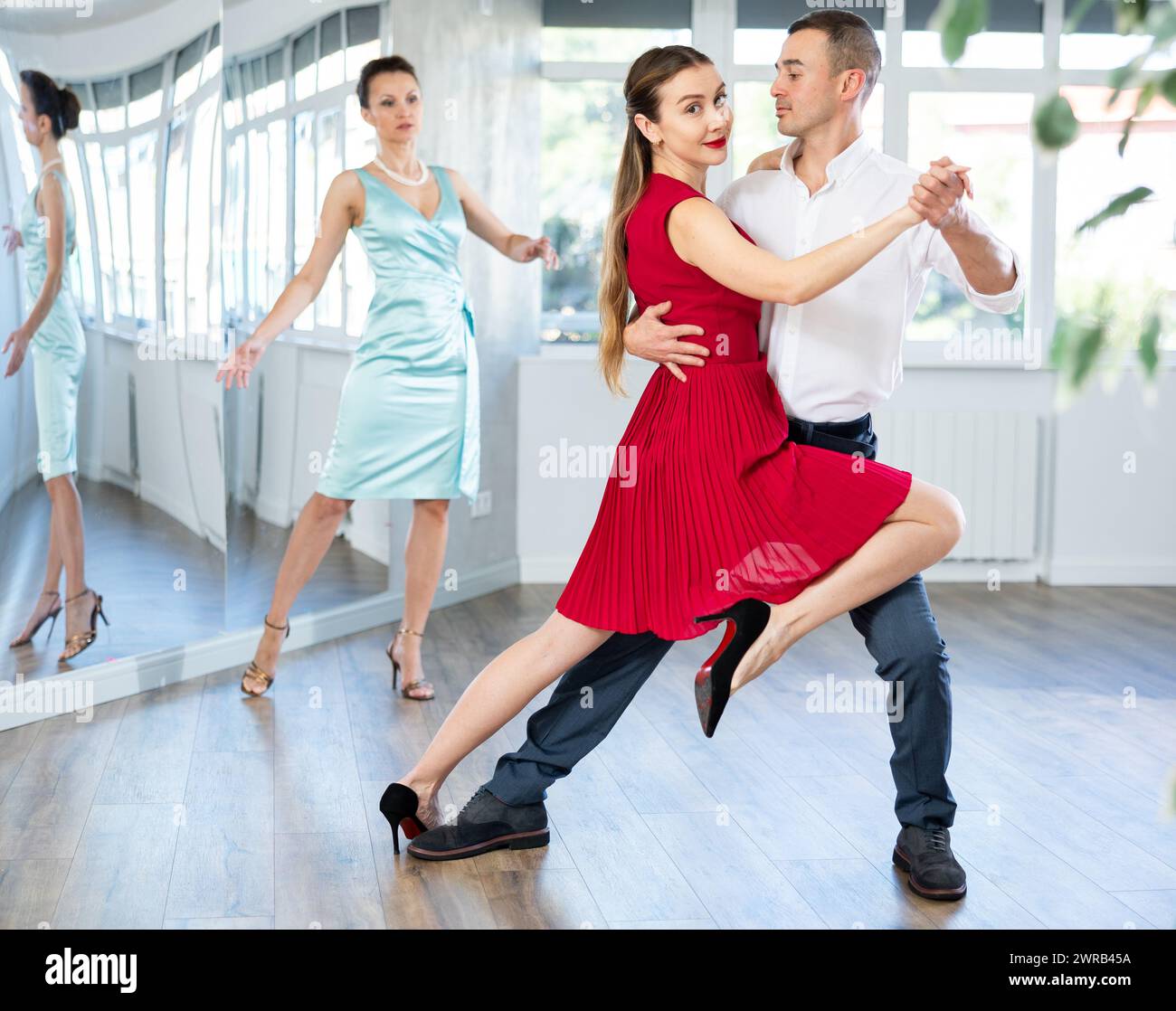 Woman in red and man in formal wear rehearsing tango in pair Stock ...