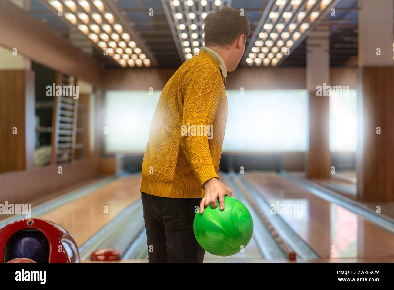 Bowler with green bowling ball ready to take his shot, poised to roll ...