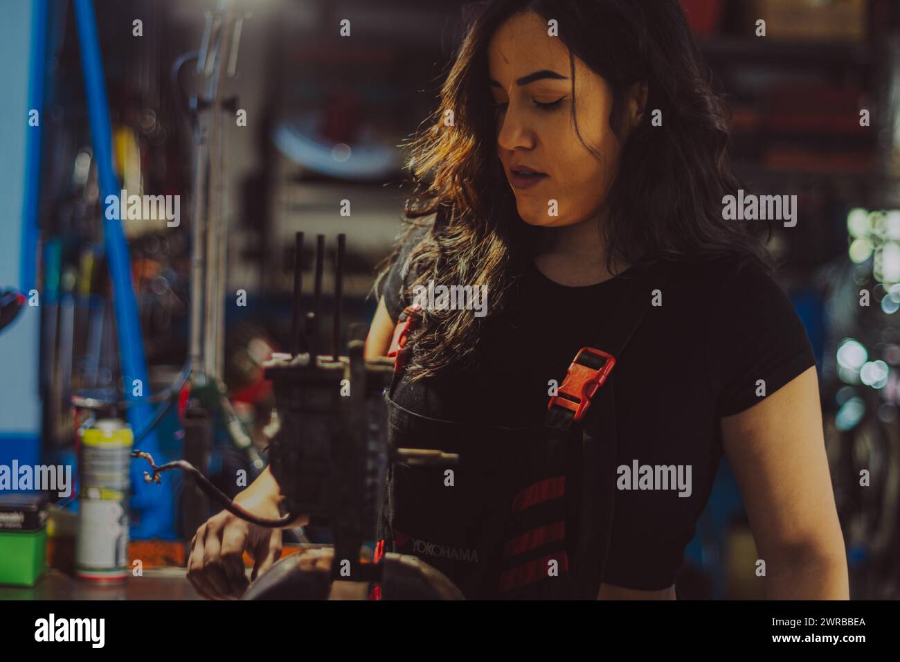 Focused mechanic female repairing a scooter engine part in a workshop ...
