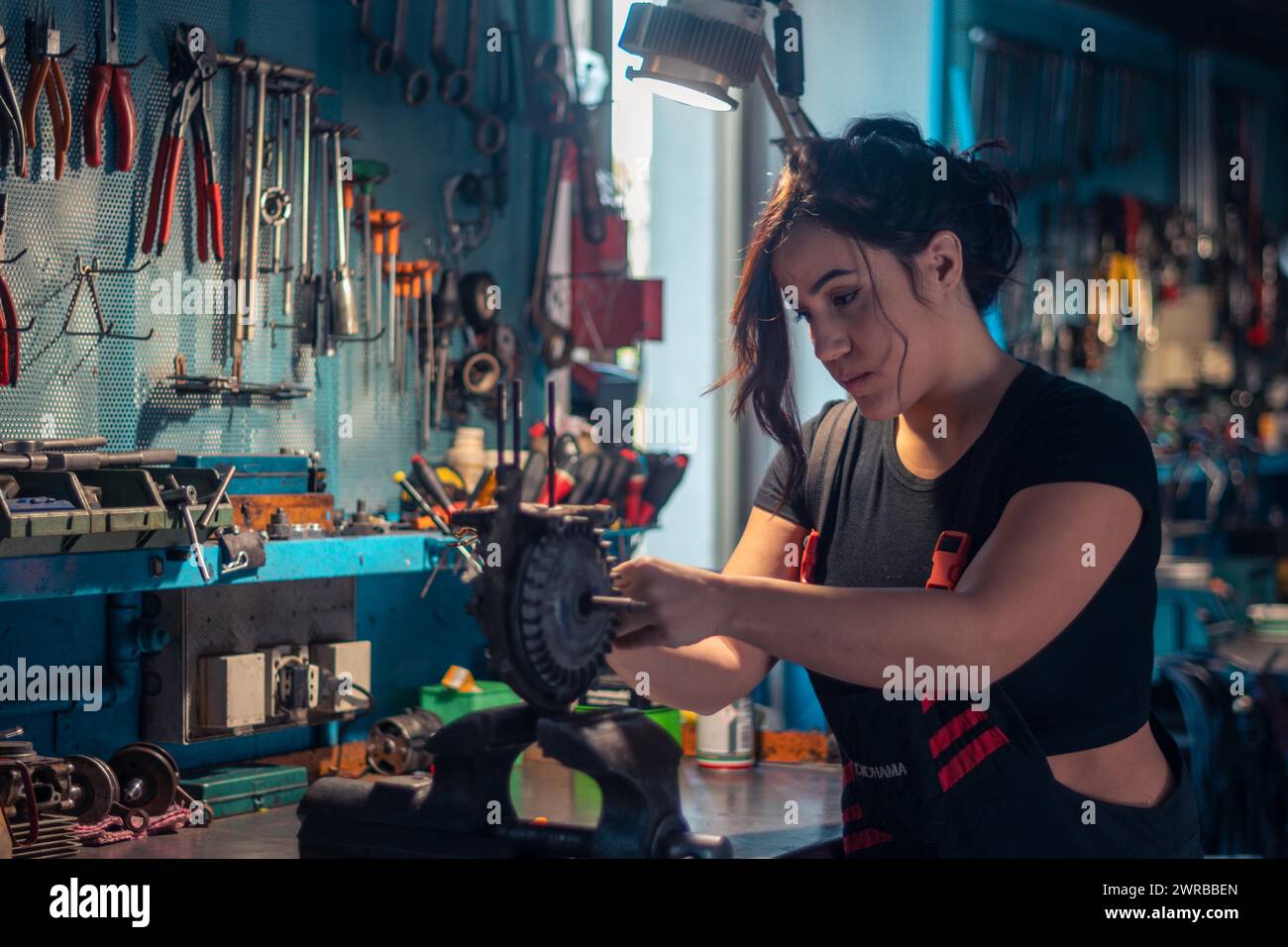 Serious young mechanic concentrating on repairing a scooter engine part ...