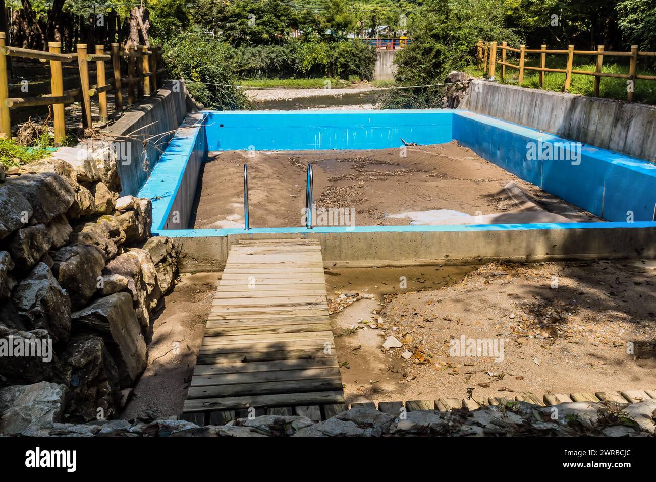 Deserted sandbox surrounded by a blue fence with a small wooden bridge ...