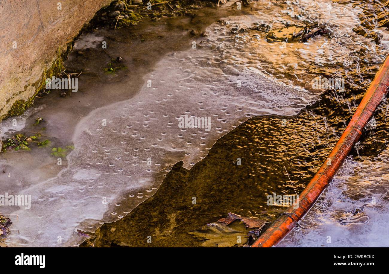 Frozen water with air bubbles trapped under the surface near a rusty ...