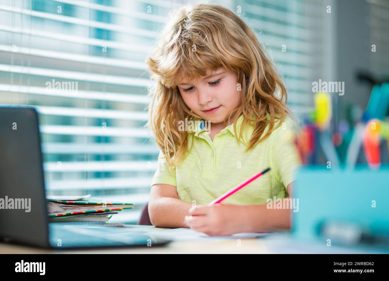 Child writing at school. Cute pupils writing at desk in classroom at ...