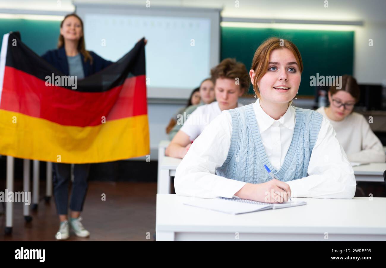 High school teacher holds the flag of Germany in her hands and talks ...