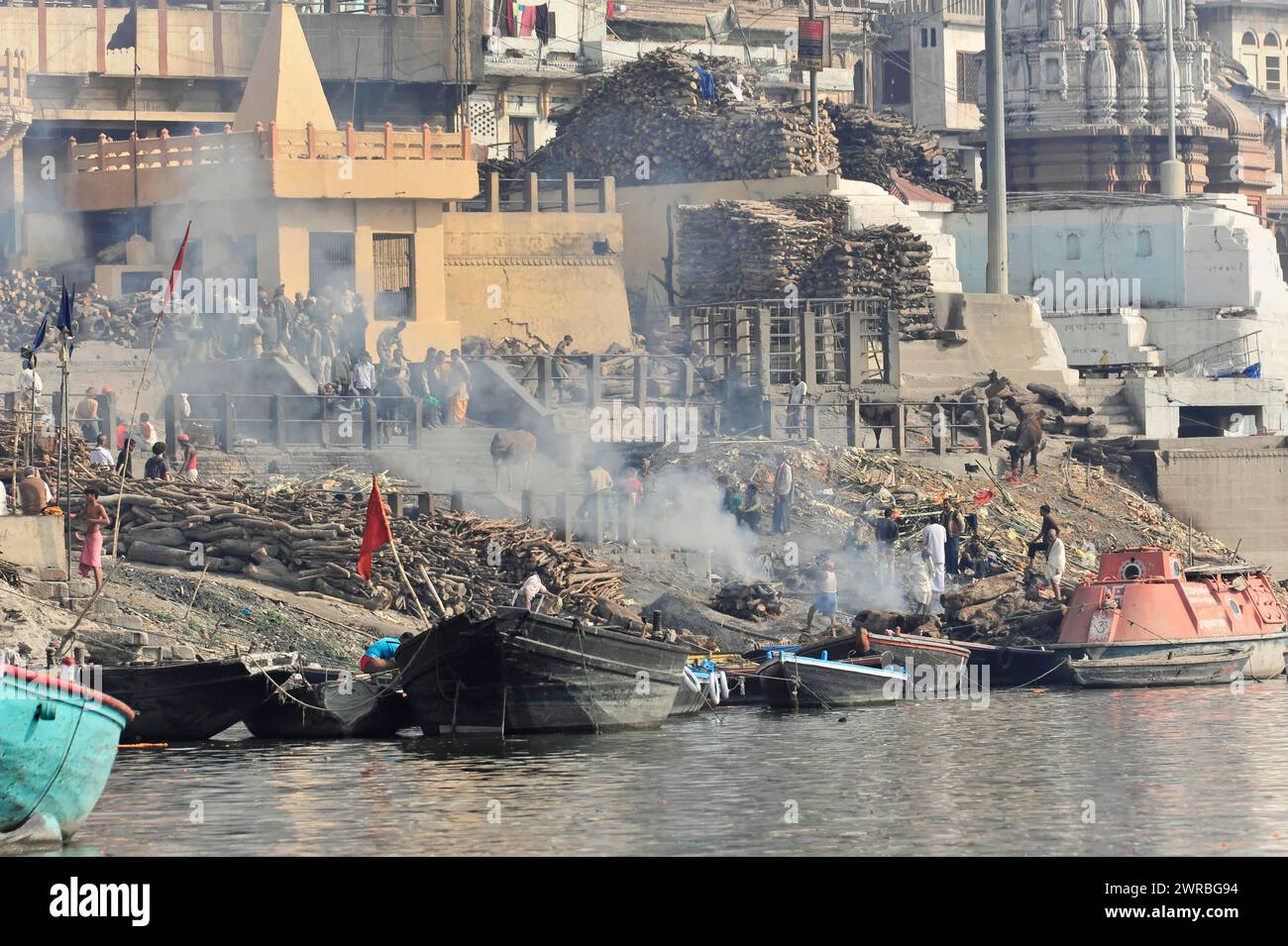 Smoke rises from a traditional funeral fire at the ghats of a river ...