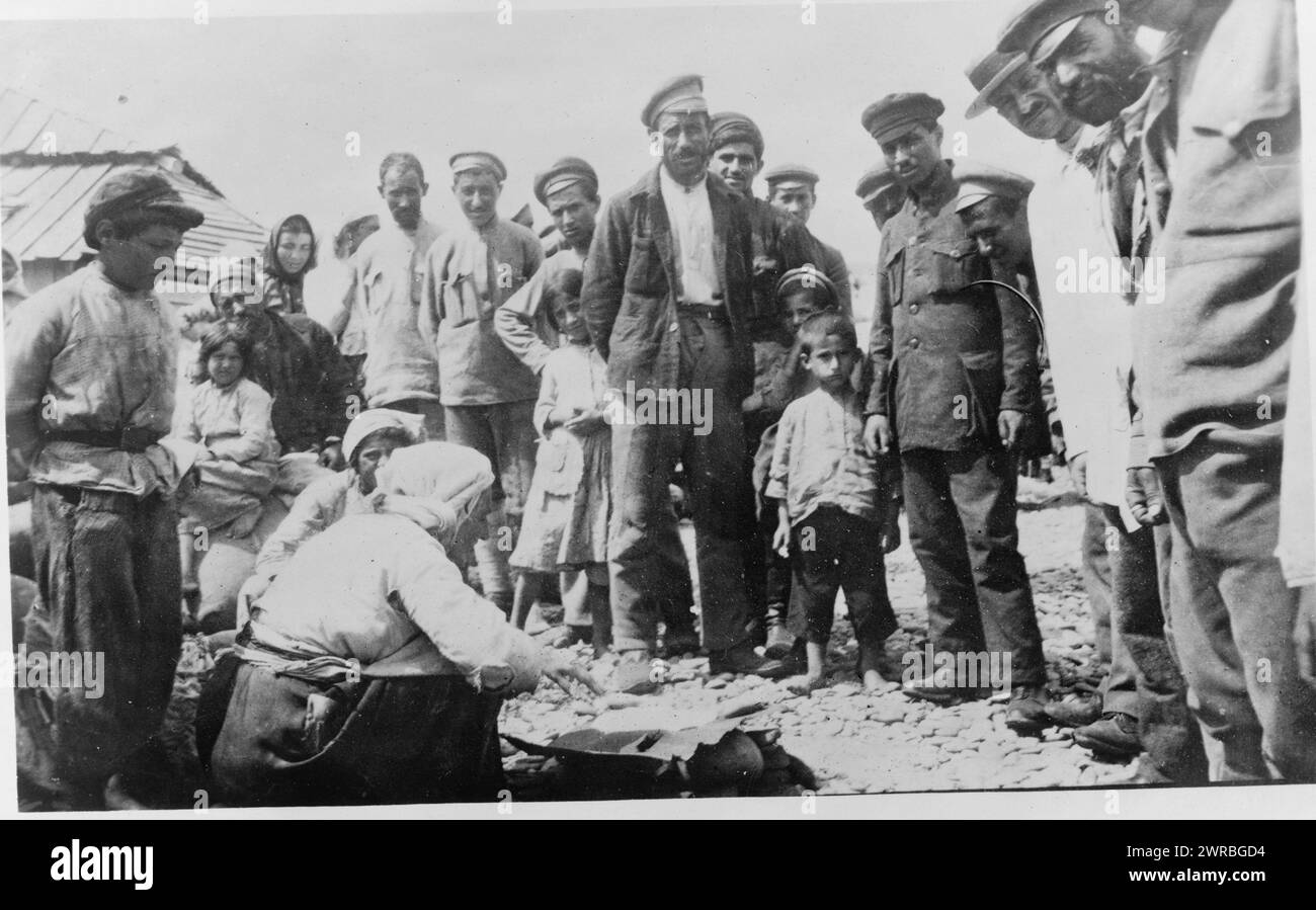 Armenian refugees on Black Sea beach, gathered around seated person ...