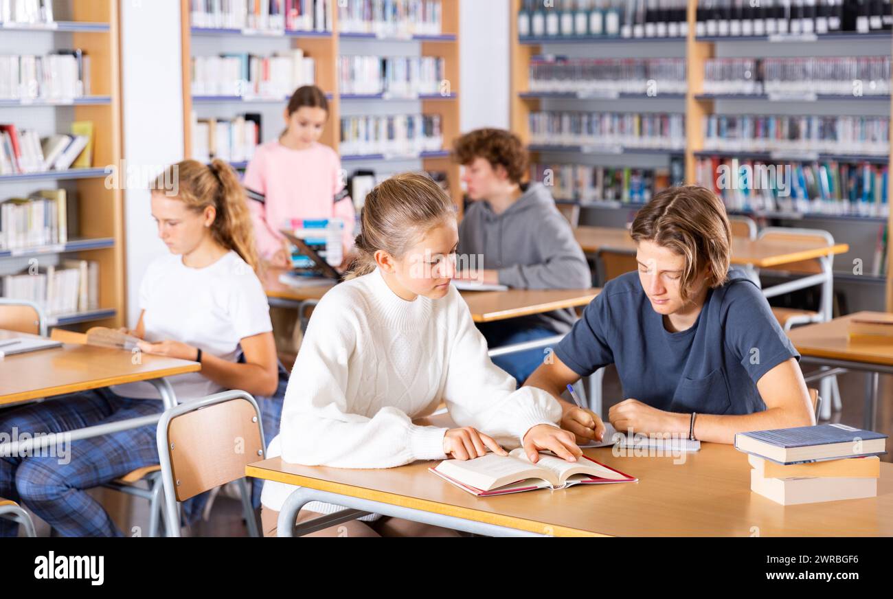 School friends spending time together in library, reading books Stock ...