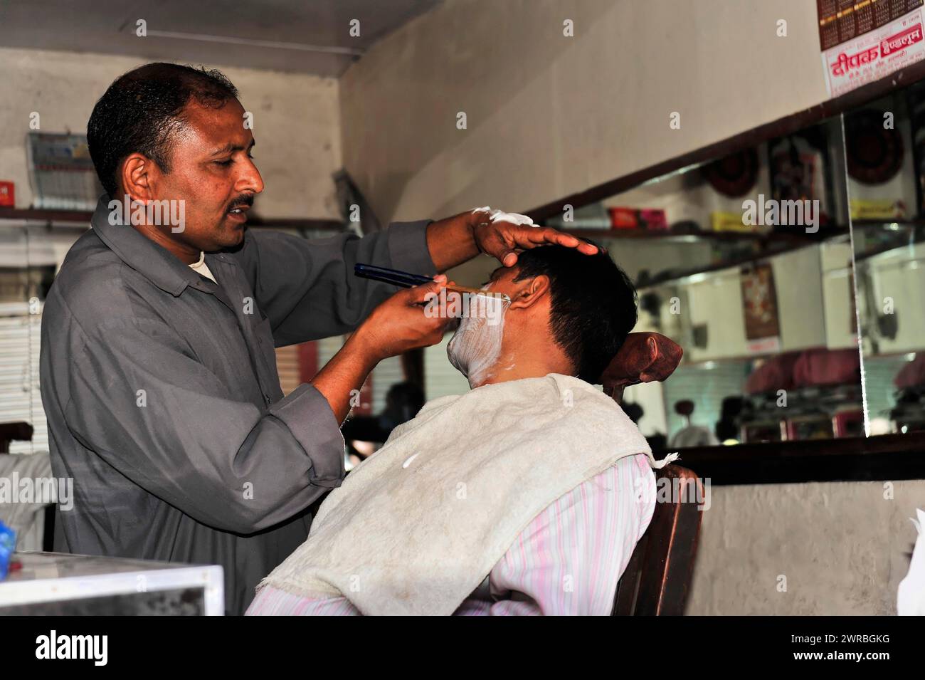 Hairdresser giving a customer a traditional shave in a hairdressing ...
